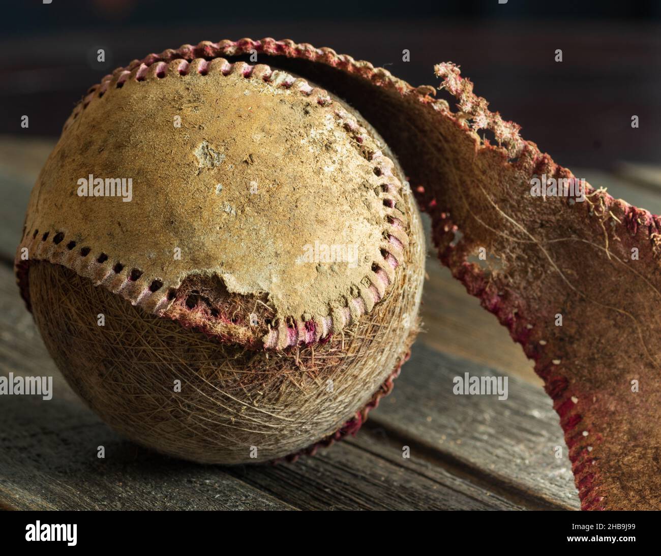 Tattered baseball on wood showing stitching and inside of baseball ...