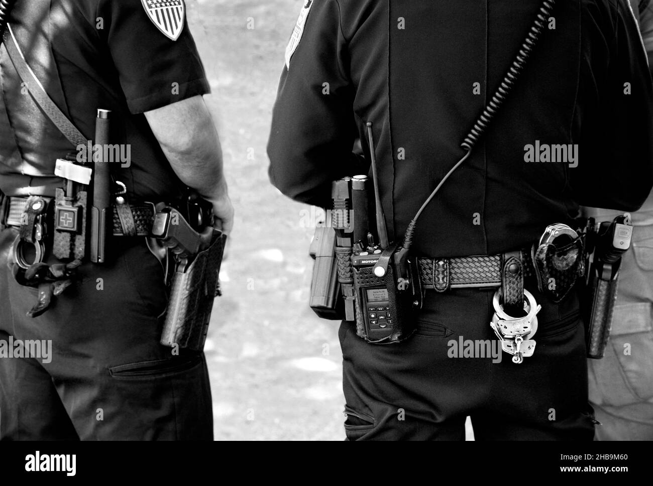 Police officers wearing belts equipped with handguns, handcuffs, radio ...