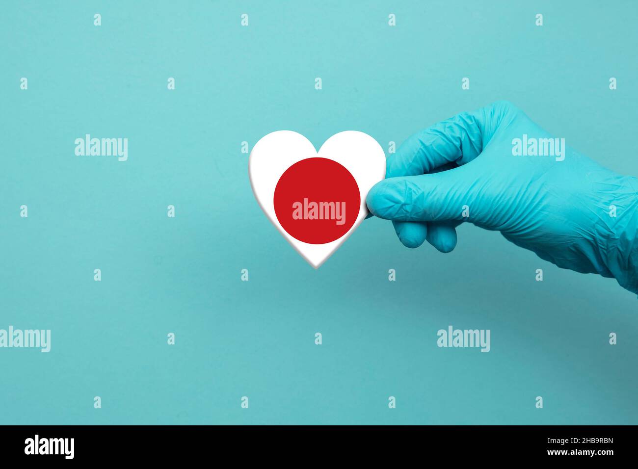 Medical workers hand wearing surgical glove holding Japan flag heart ...