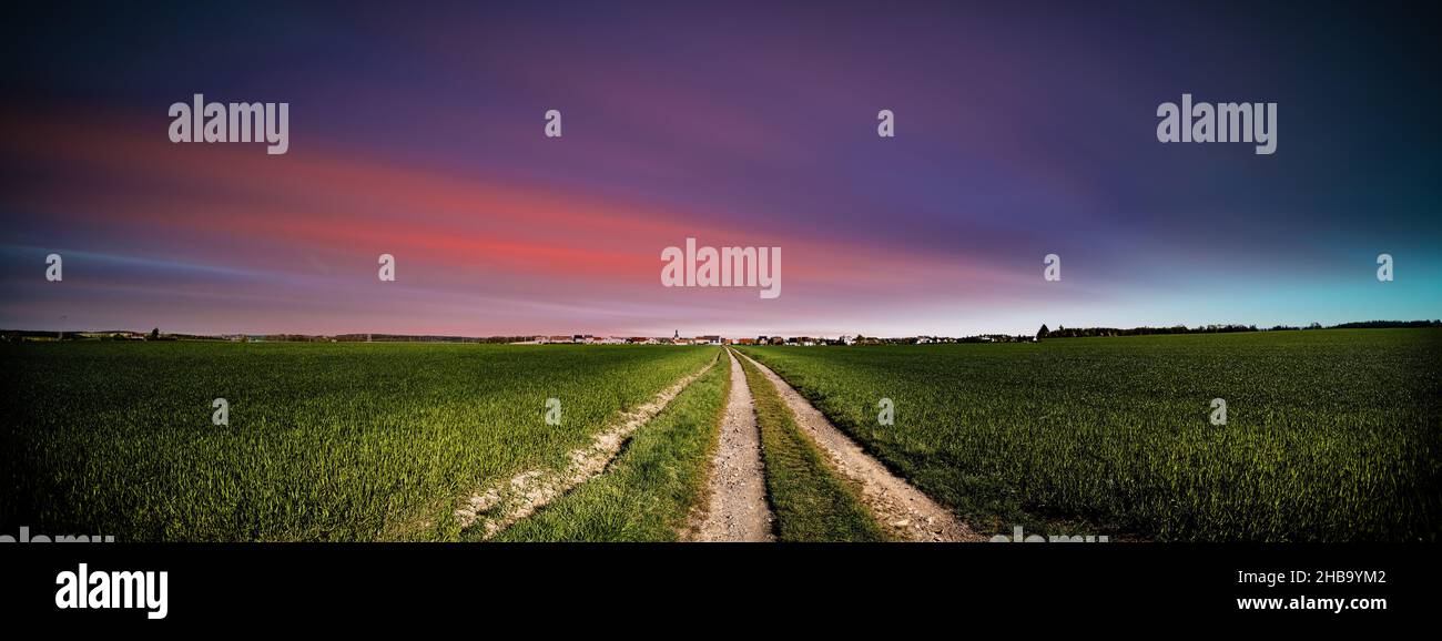 Field with dirt road and sunset sky Stock Photo - Alamy