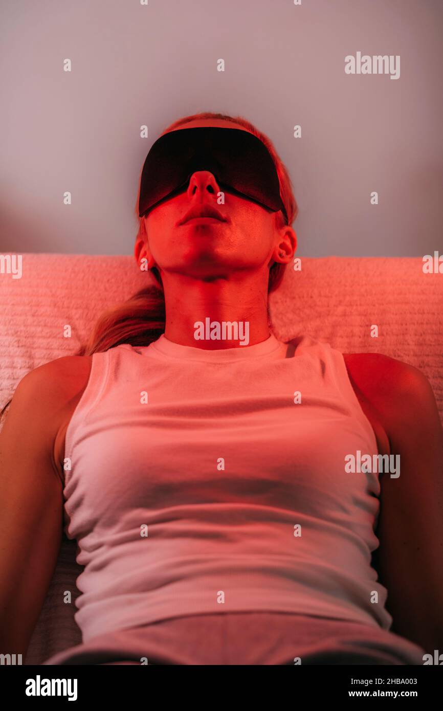 Colour light therapy. Female face under the red light Stock Photo - Alamy