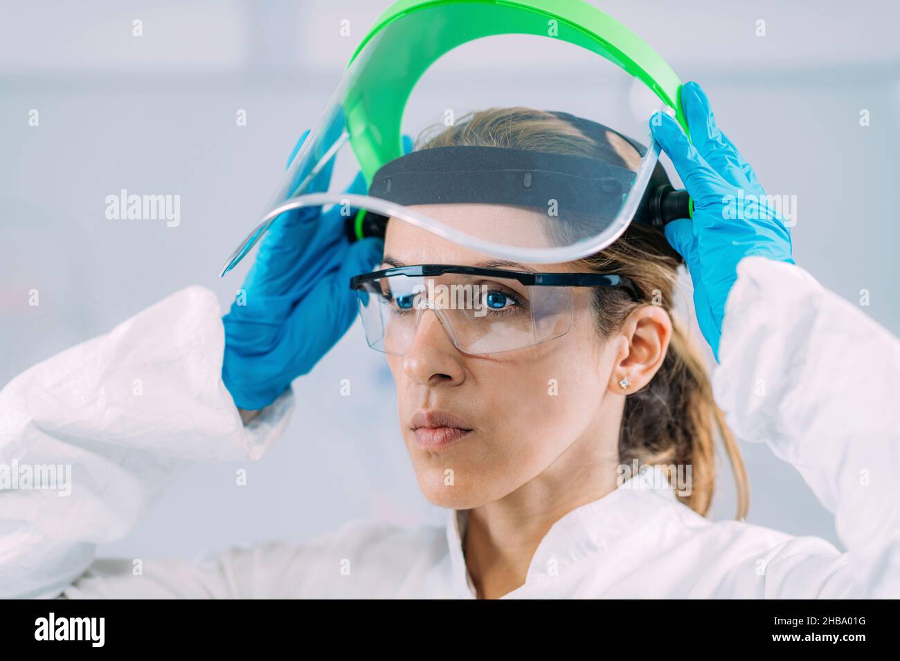 Lab technician putting protective face shield on Stock Photo - Alamy