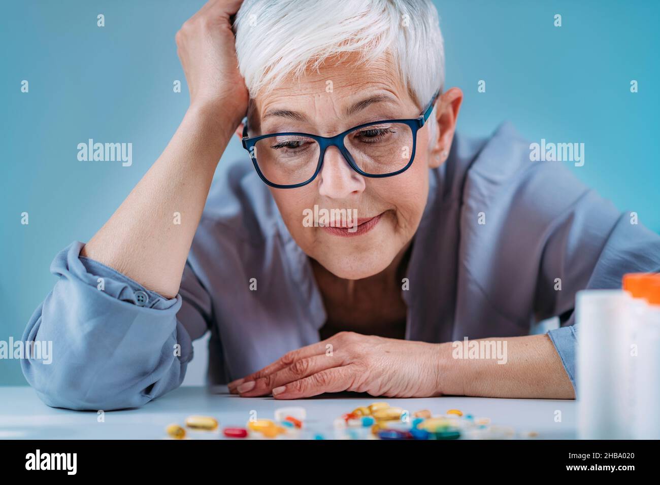 Medicine non adherence, conceptual image. Senior woman looking at her ...