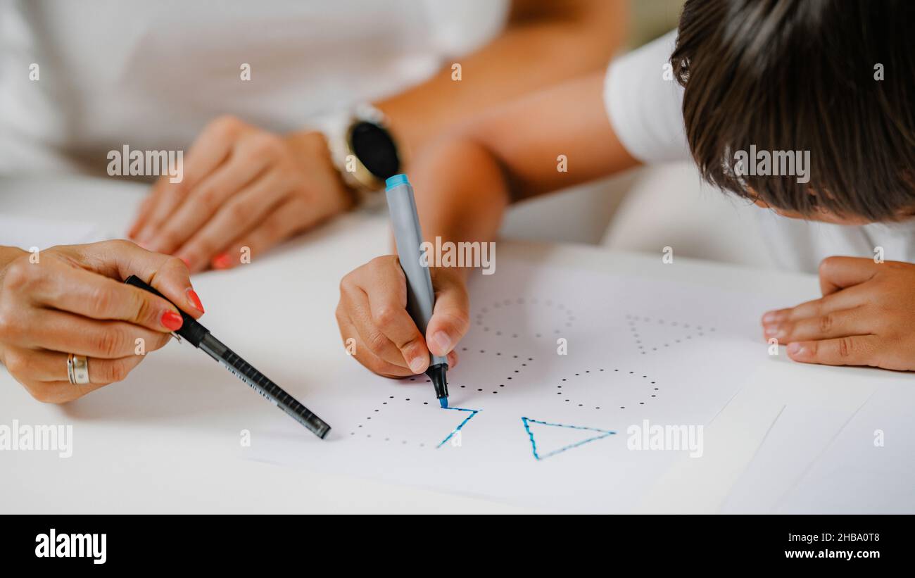 Child drawing shapes in a pre-schooler assessment, psychologist helping ...