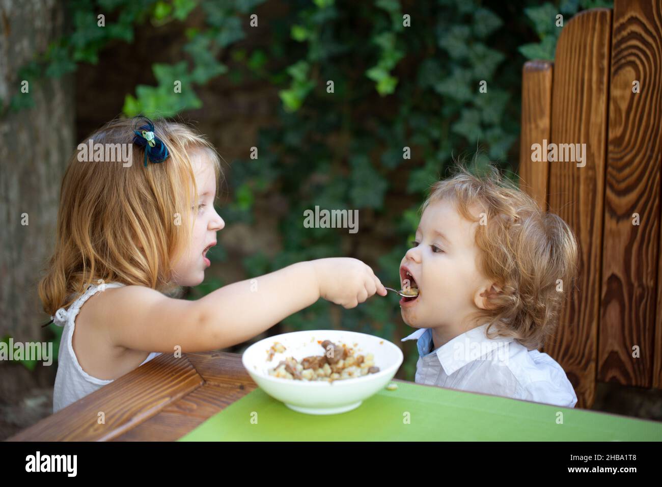 Cute baby food, babies eating. Little girl sister feeding baby. Good ...