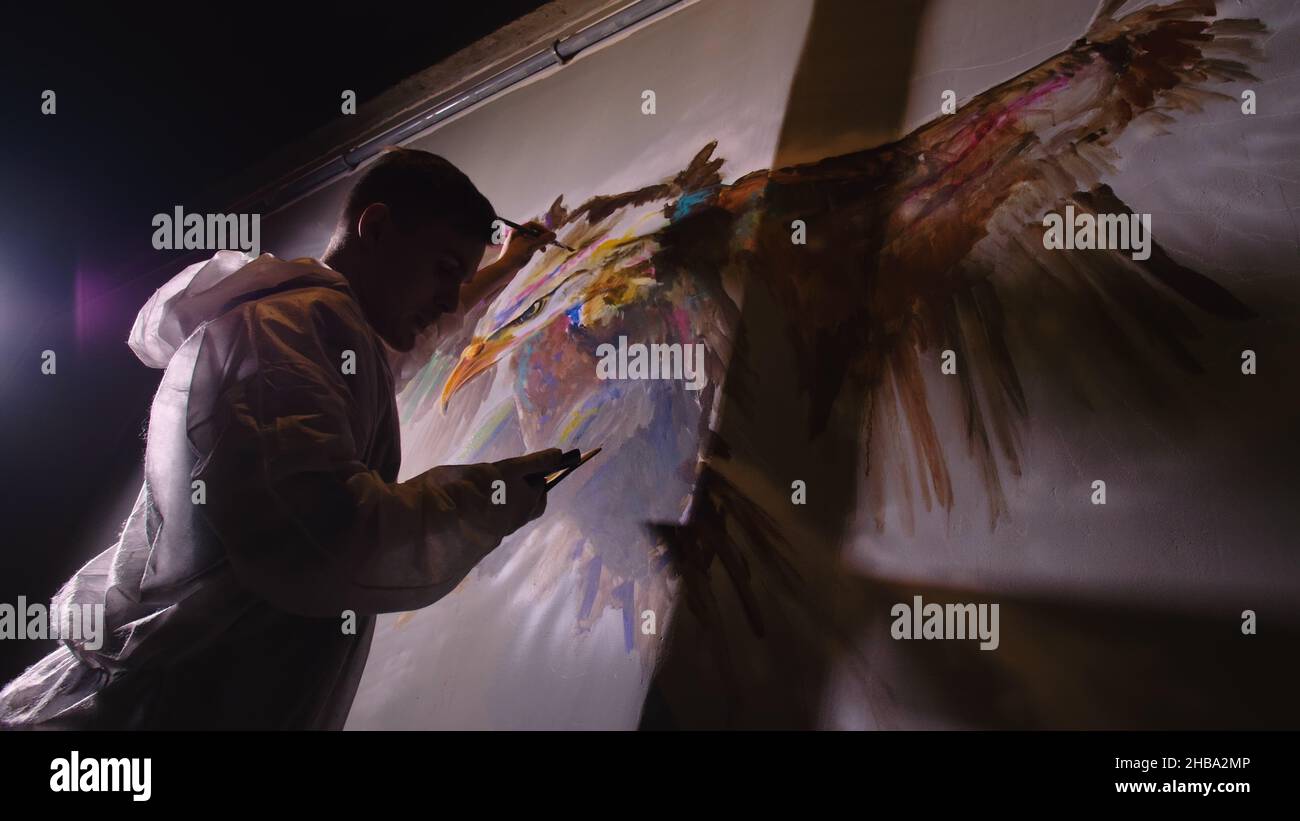 Artist designer draws an eagle on wall. Craftsman decorator paints ...