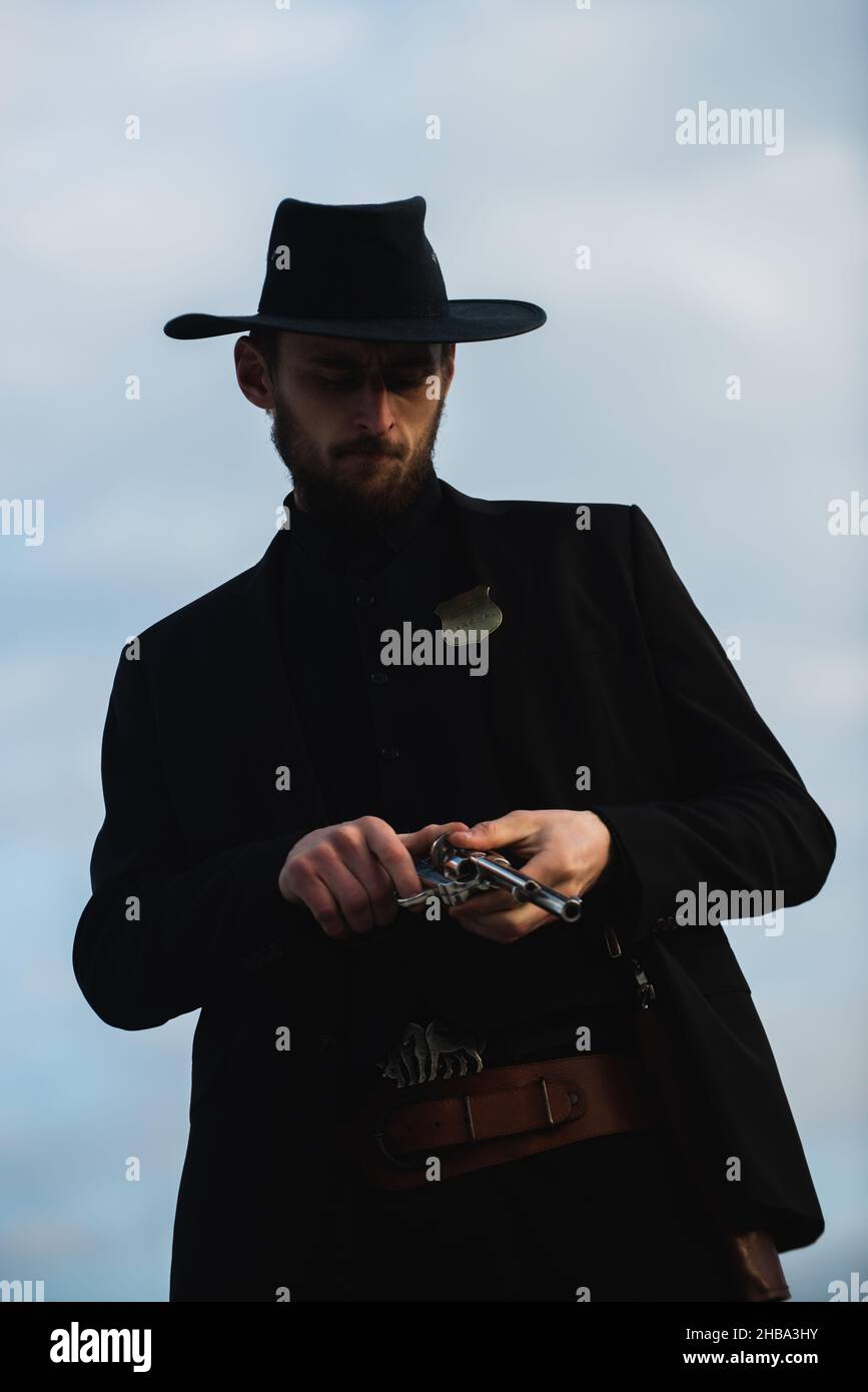 Cowboy shooter in black suit and cowboy hat. Serious man with wild west ...