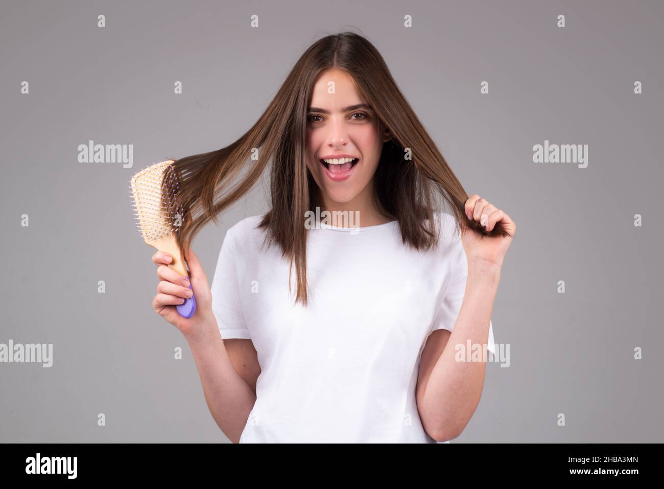 Woman is making hairstyle with comb. Beautiful young woman holding ...