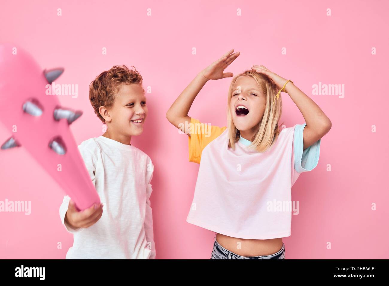 Cheerful boy and girl rubber pink baton toy fun Stock Photo - Alamy