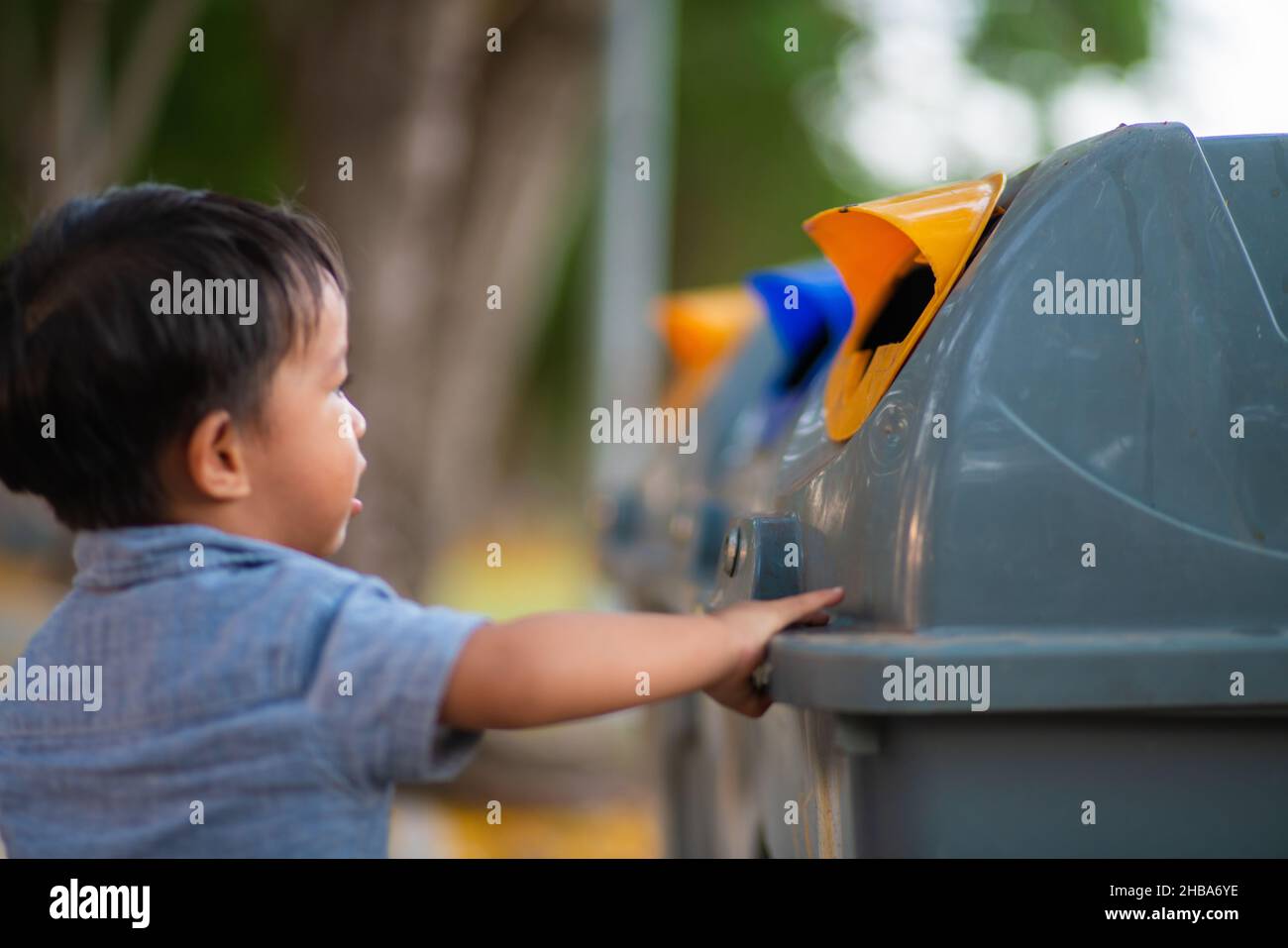 Toddler boy keep trash to bin in city park environment clean concept ...