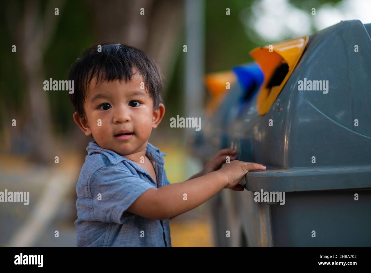 Toddler boy keep trash to bin in city park environment clean concept ...