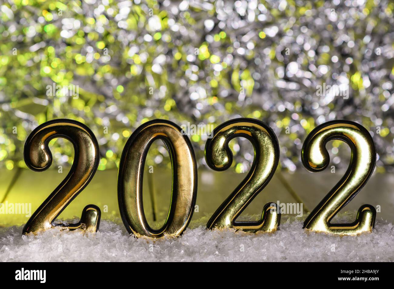 Gold numbers 2022 on snow with yellow backlight. New year backdrop with ...