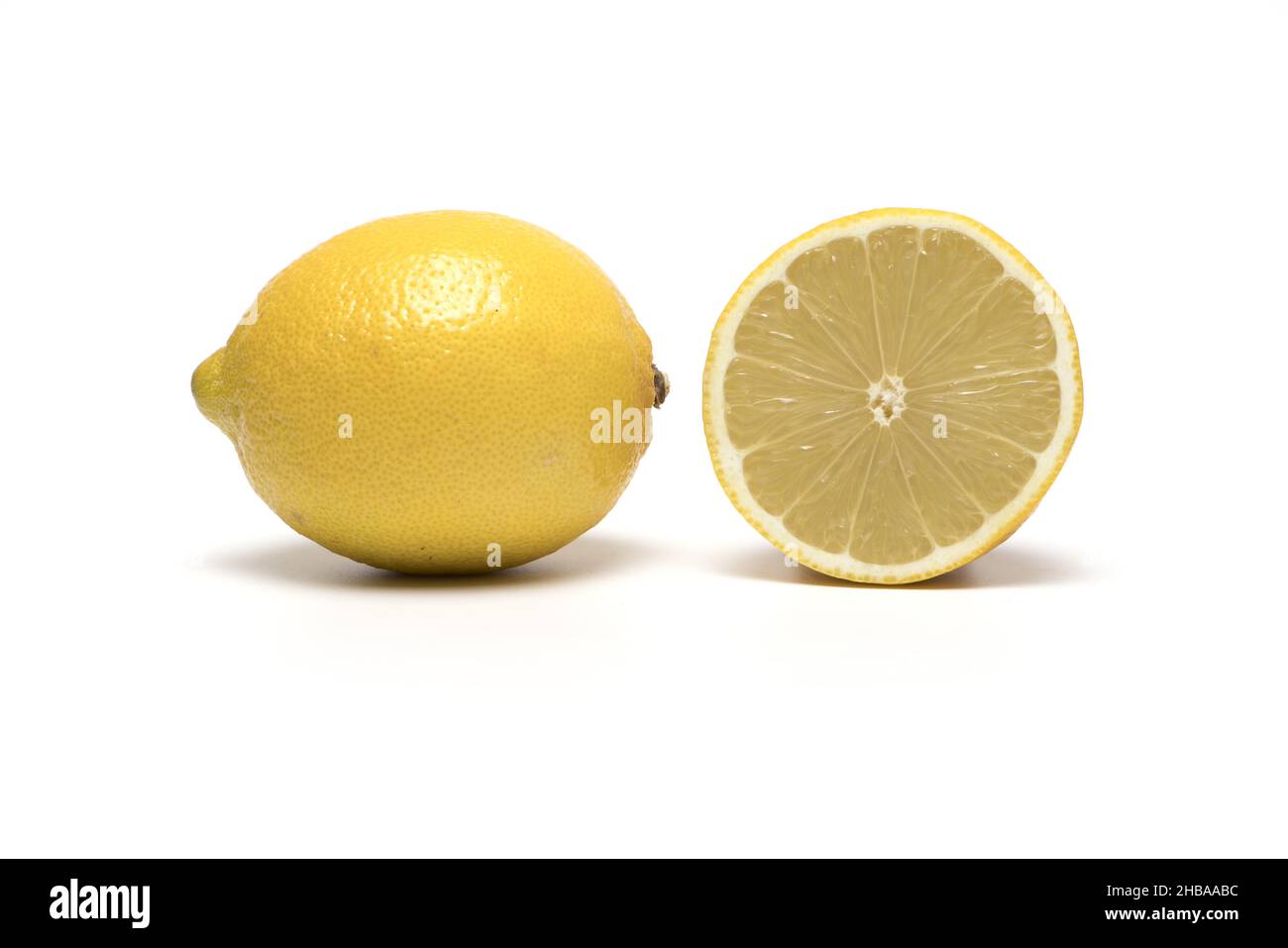 a ripe lemon next to a cut lemon half isolated on white background ...