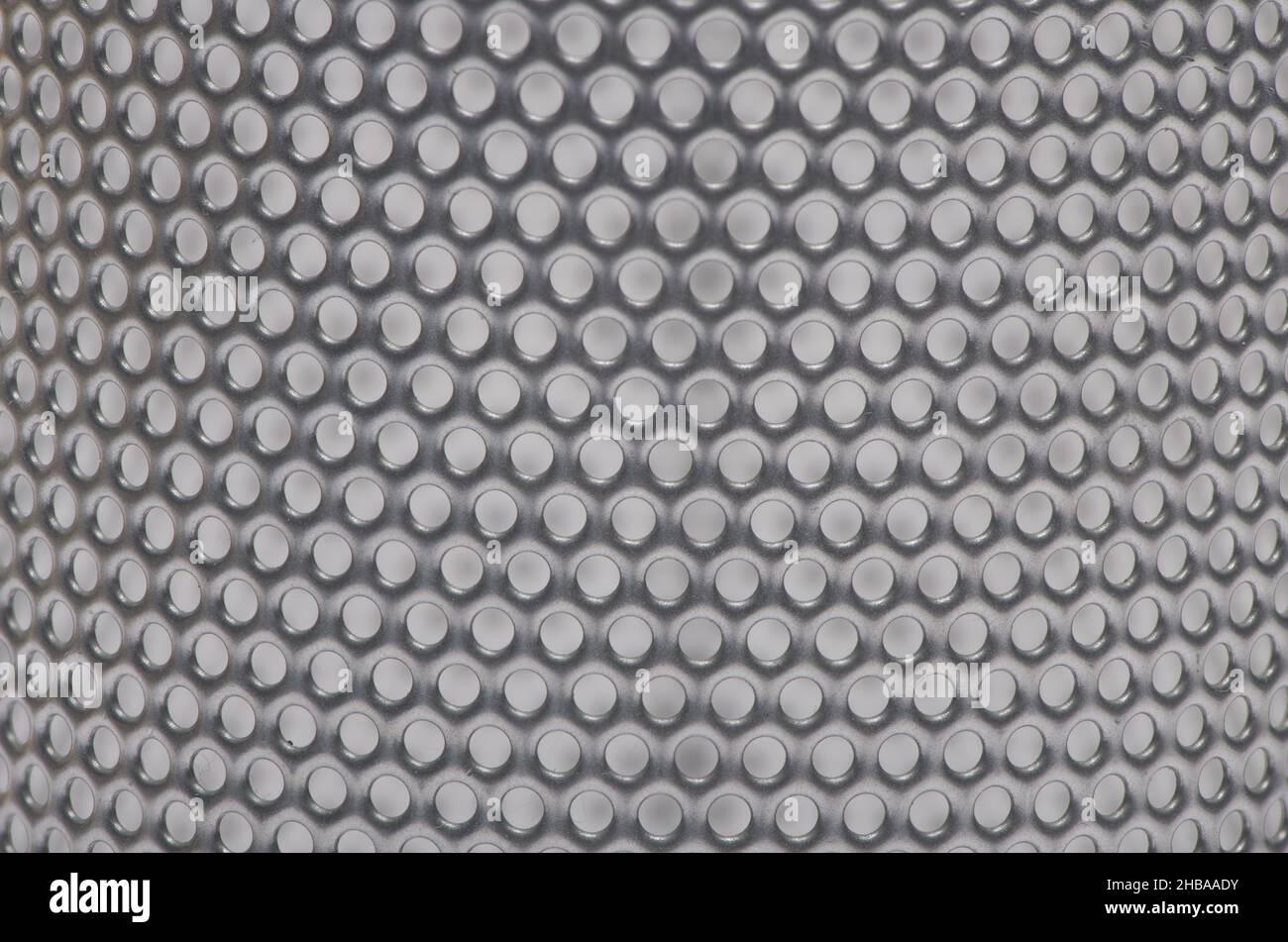 Close up of round curved silver gray metal perforated sheet to use as ...
