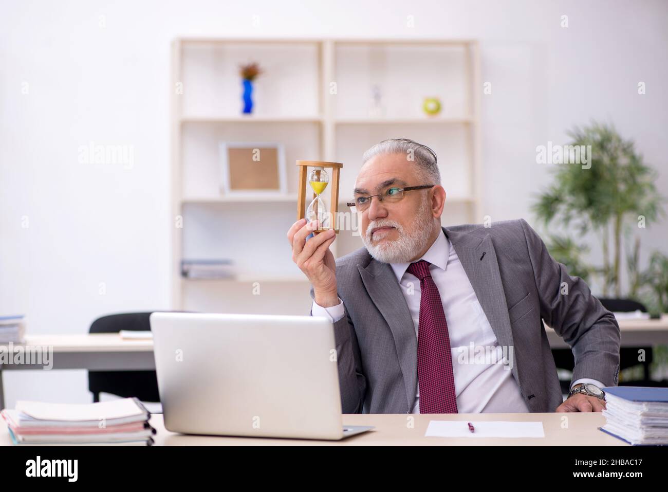 Old employee in time management concept Stock Photo - Alamy