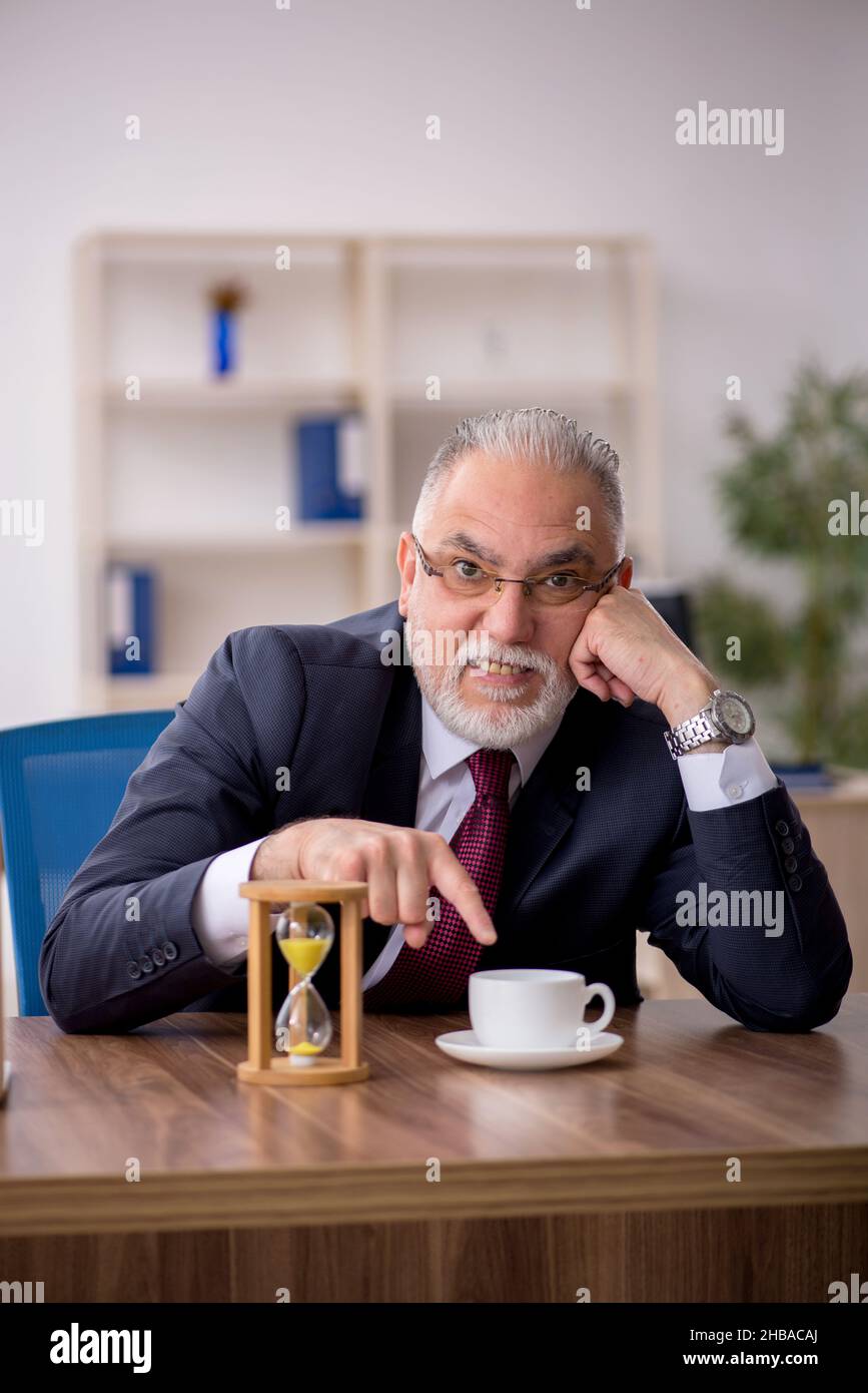 Old employee in time management concept Stock Photo - Alamy