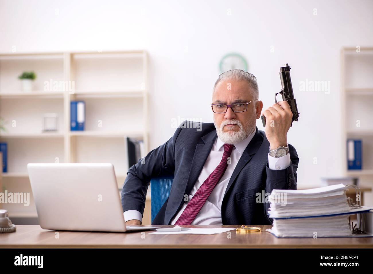 Old male employee holding gun at workplace Stock Photo - Alamy