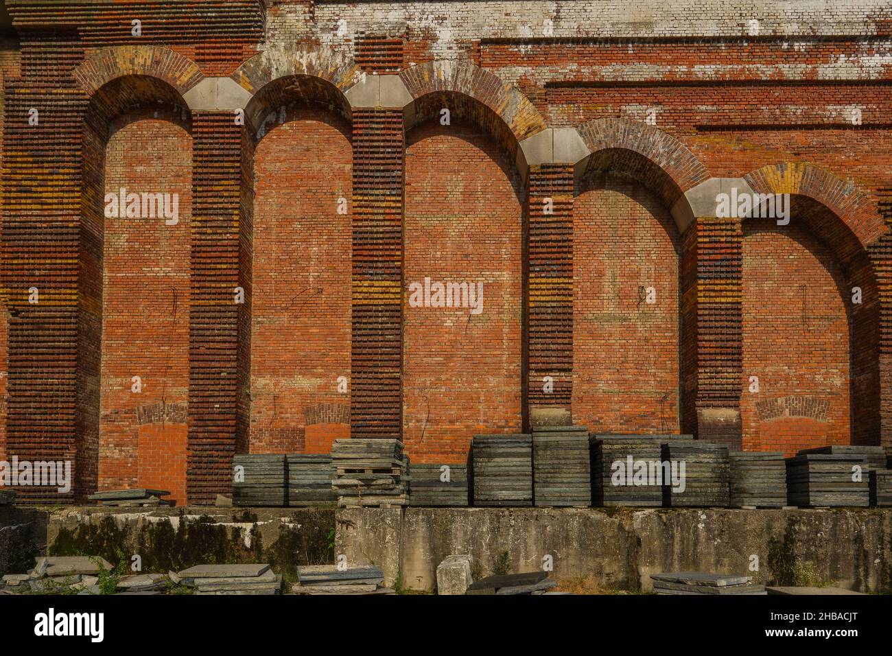 Stacks of concrete paving slabs tiles in front of an arched brick ...