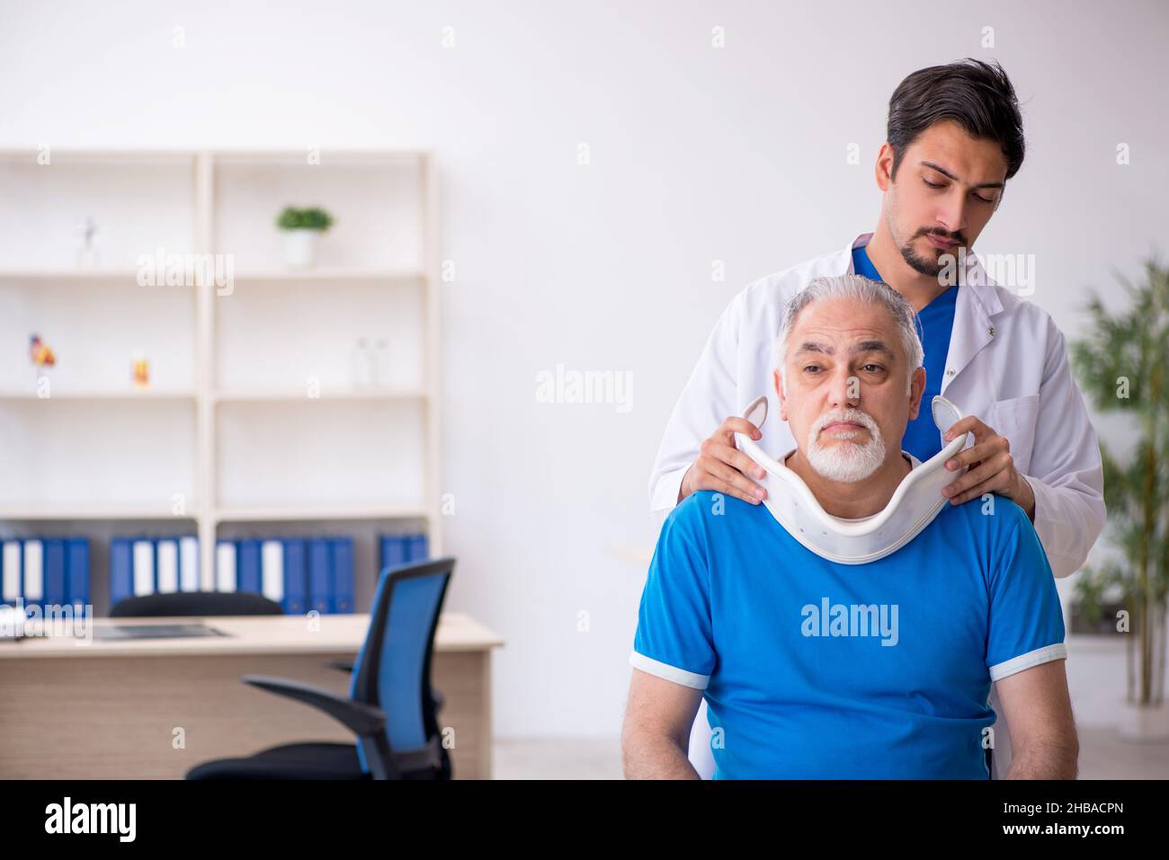 Old neck injured patient visiting young male doctor Stock Photo - Alamy