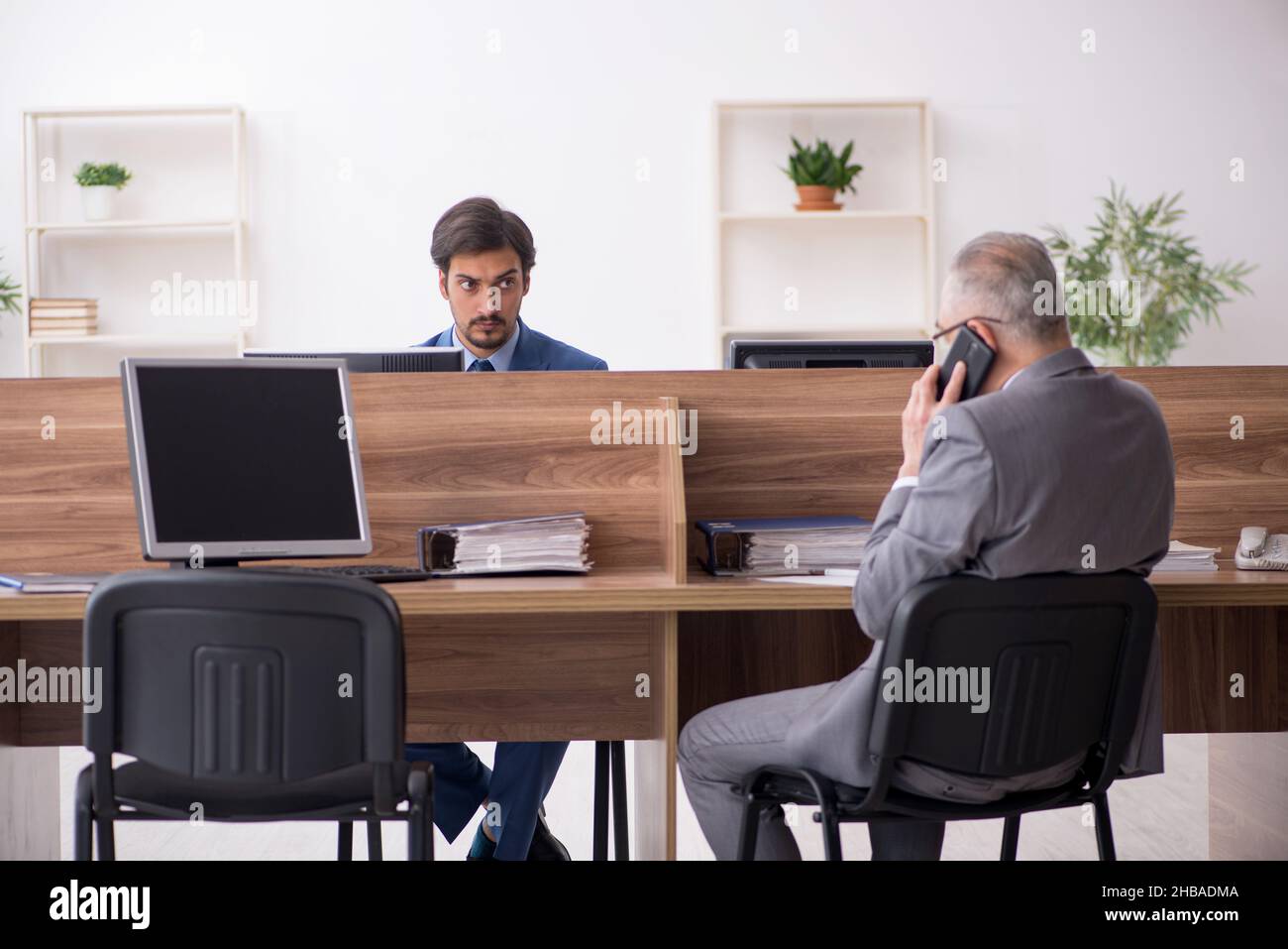 Two male employees working at workplace Stock Photo - Alamy