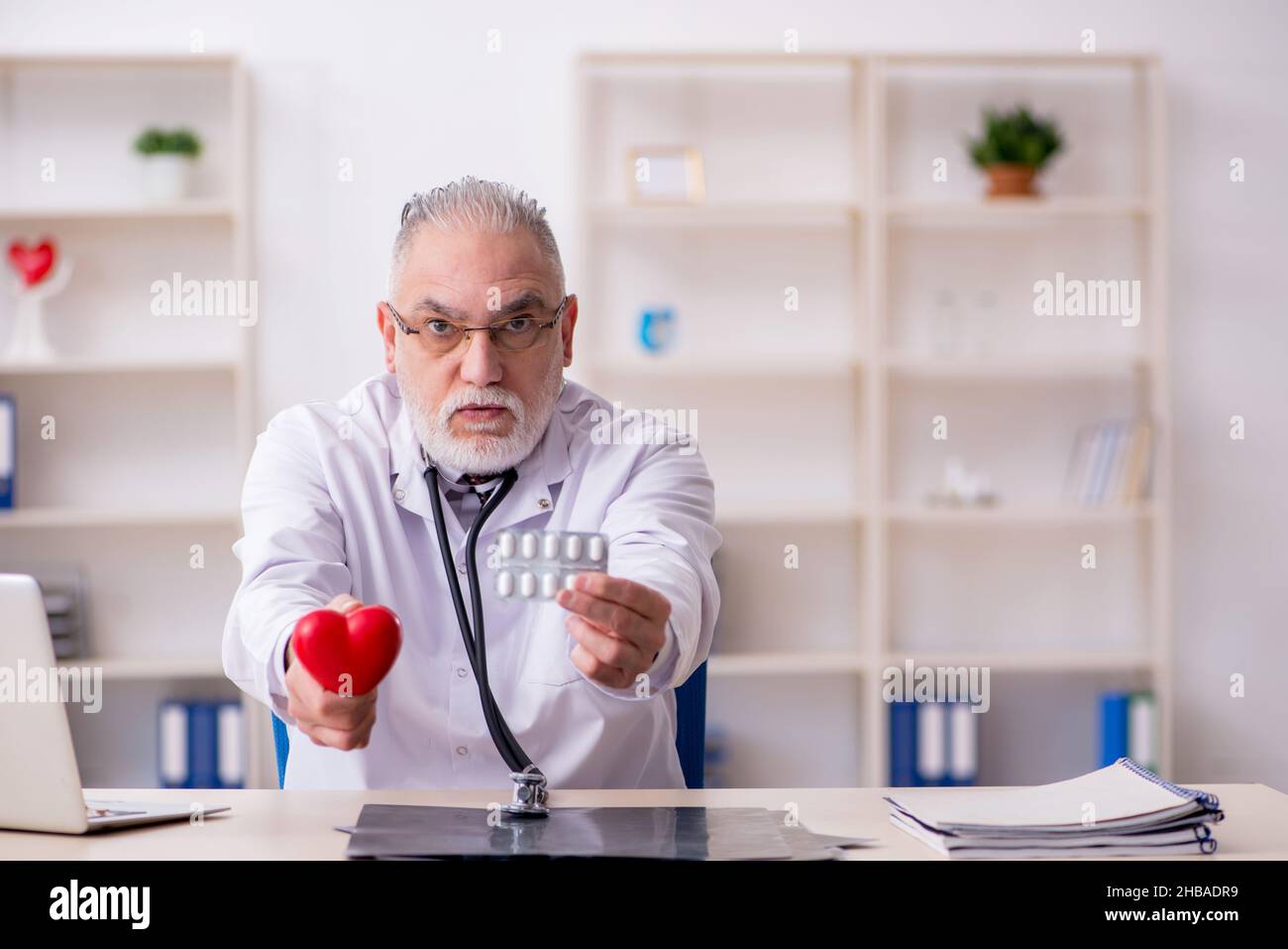 Old doctor cardiologist working in the clinic Stock Photo - Alamy