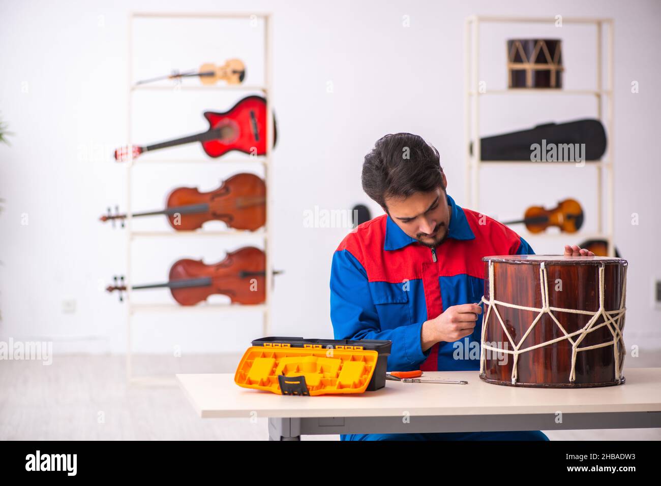 Young repairman repairing musical instruments at workplace Stock Photo ...