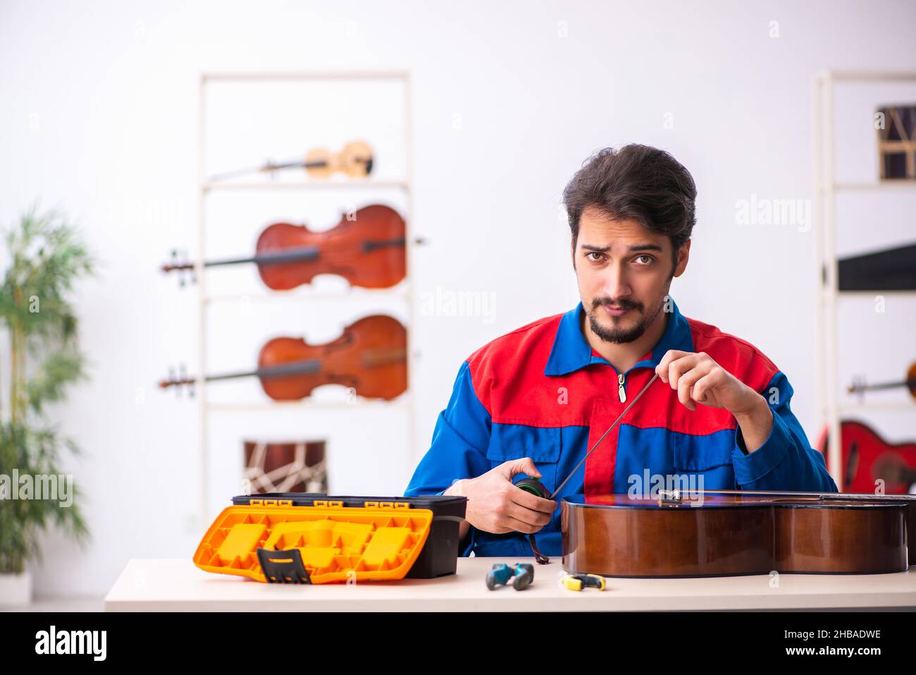 Young repairman repairing musical instruments at workplace Stock Photo ...