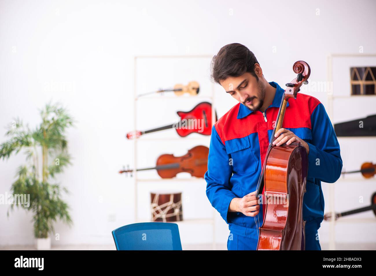 Young repairman repairing musical instruments at workplace Stock Photo ...