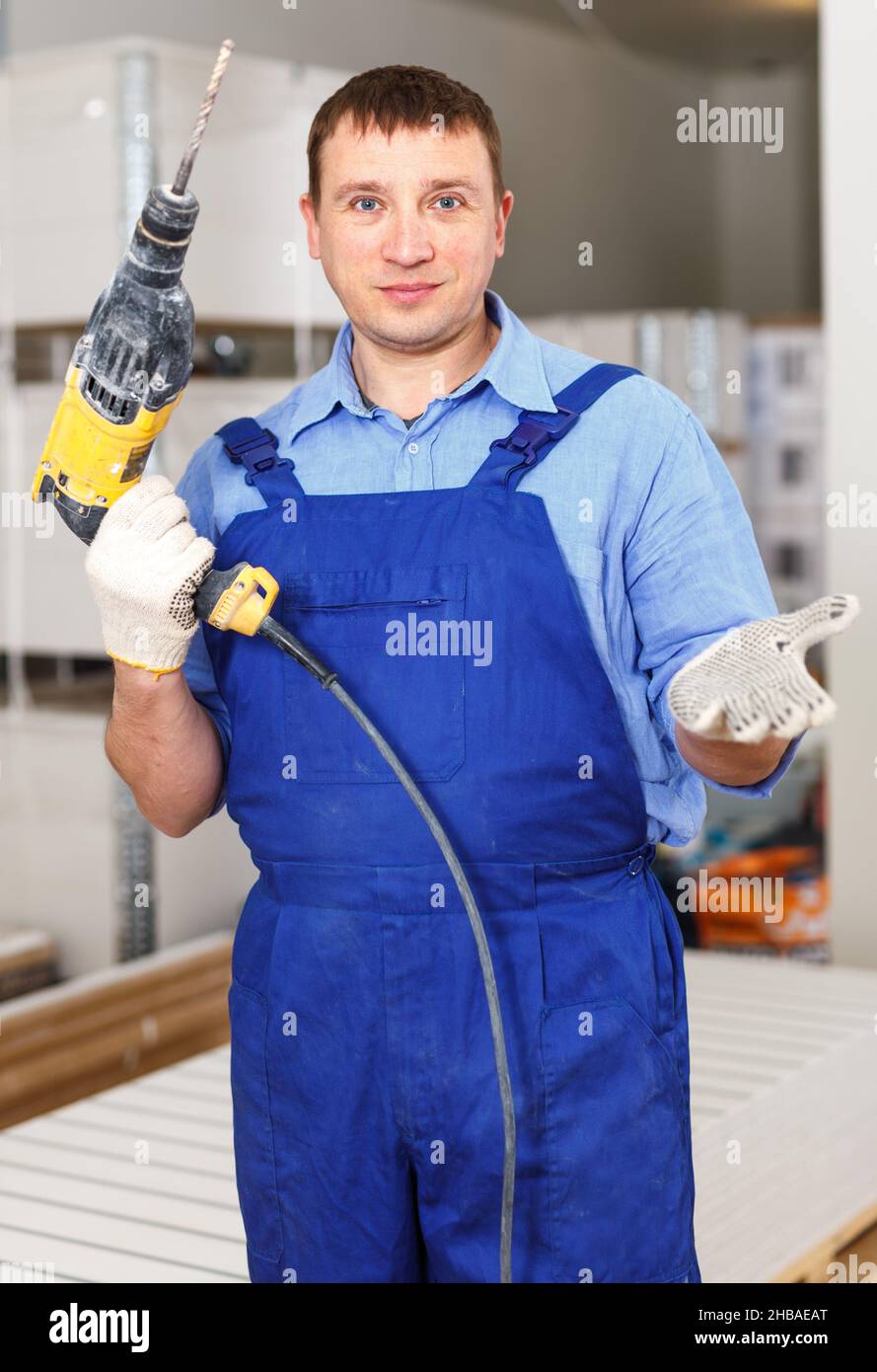 Construction worker holding electric perforator Stock Photo - Alamy