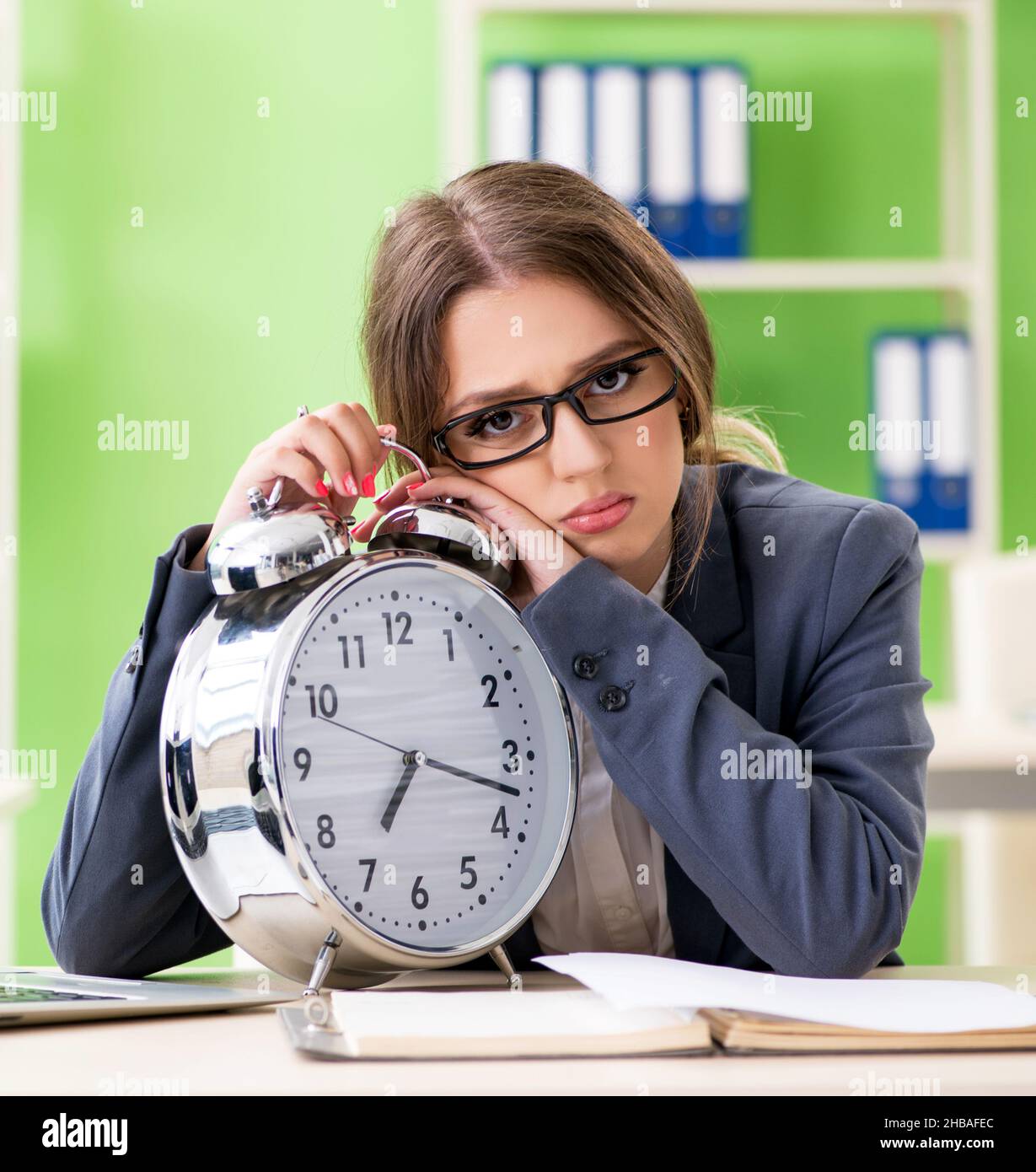Young female employee very busy with ongoing paperwork in time ...