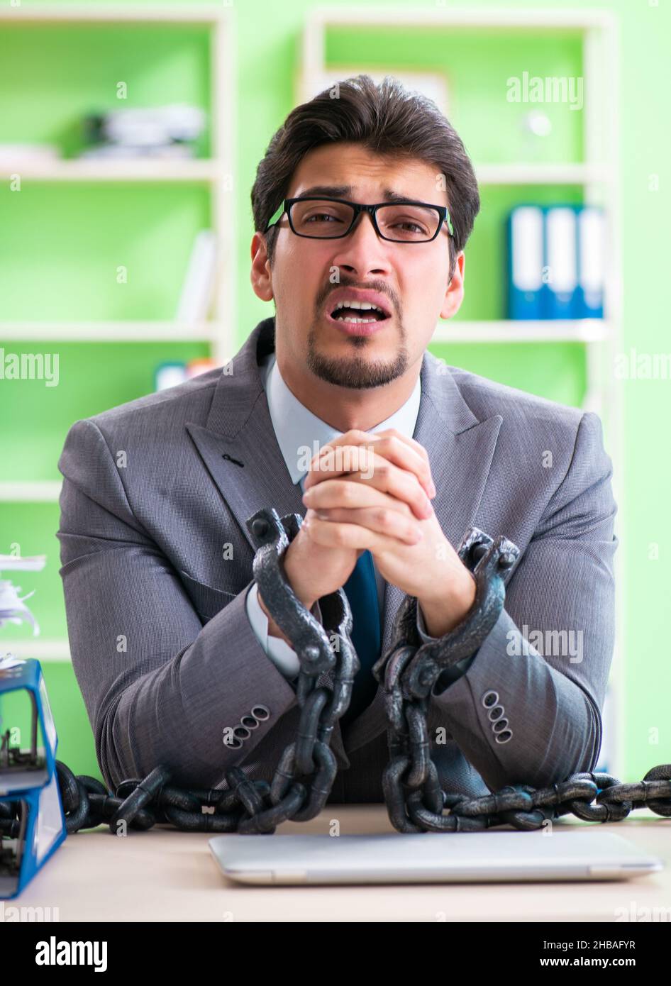 The employee chained to his desk due to workload Stock Photo - Alamy