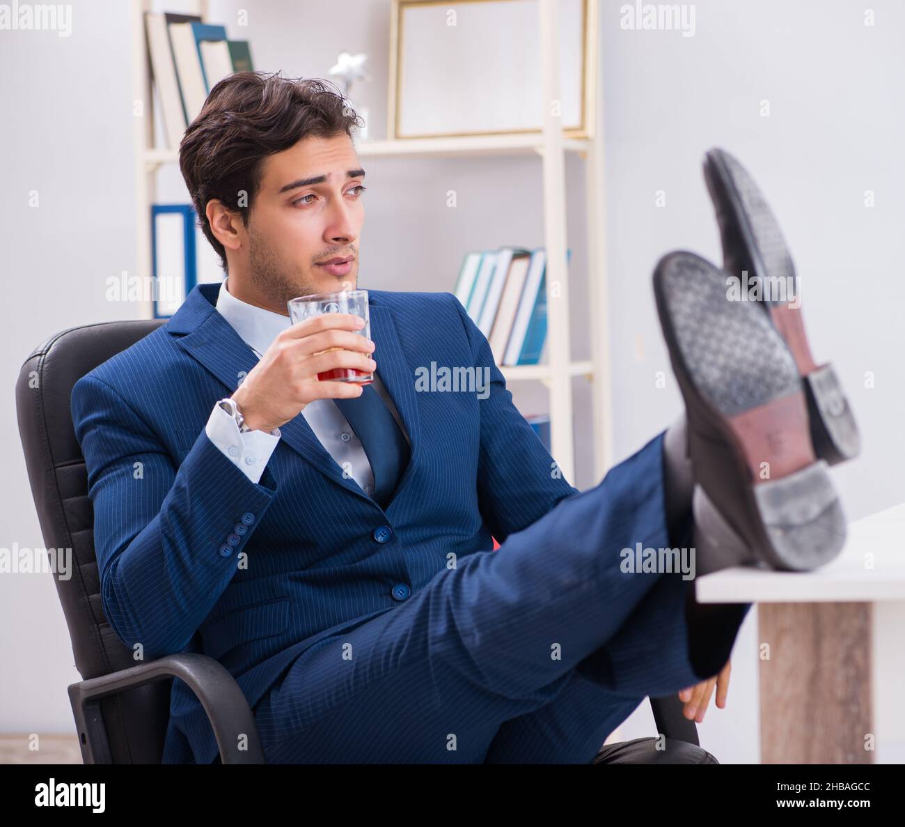 The young businessman employee drinking in the office at desk Stock ...