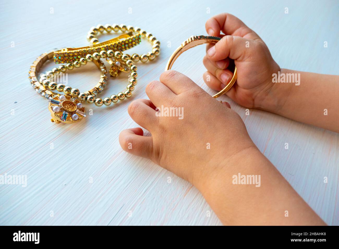 childrens hands play with gold jewelry and bijouterie, on white ...