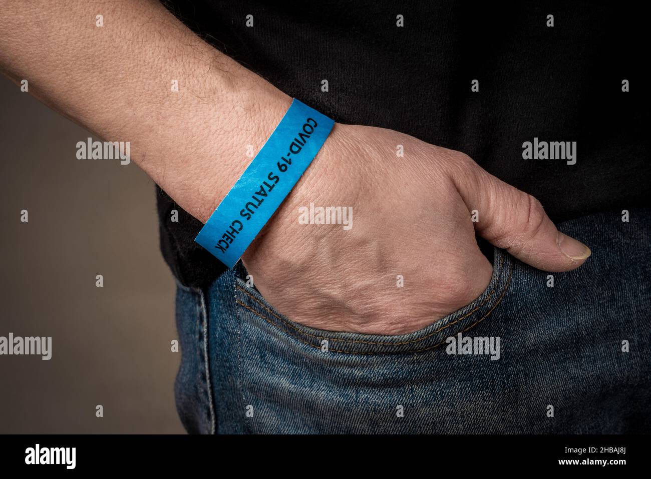 Closeup of Covid-19 Status Check wristband on a caucasian male. Hand ...
