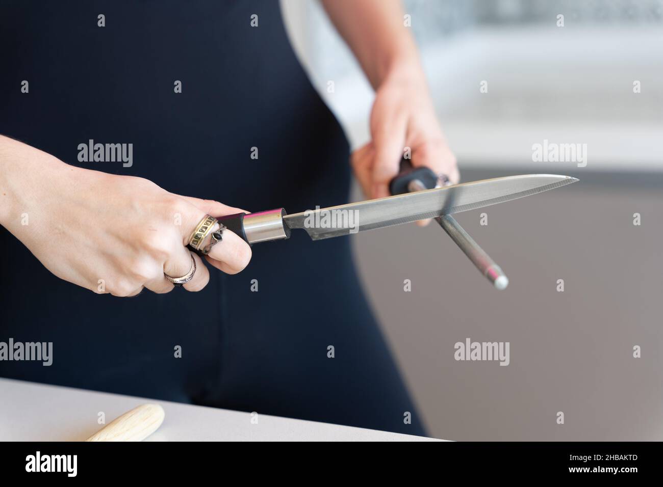 woman sharpening a knife with a grinder, close-up view with blurred ...