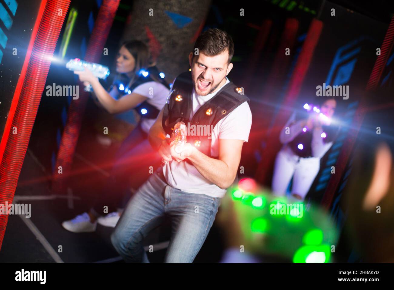 Emotional guy playing laser tag in colorful beams Stock Photo - Alamy