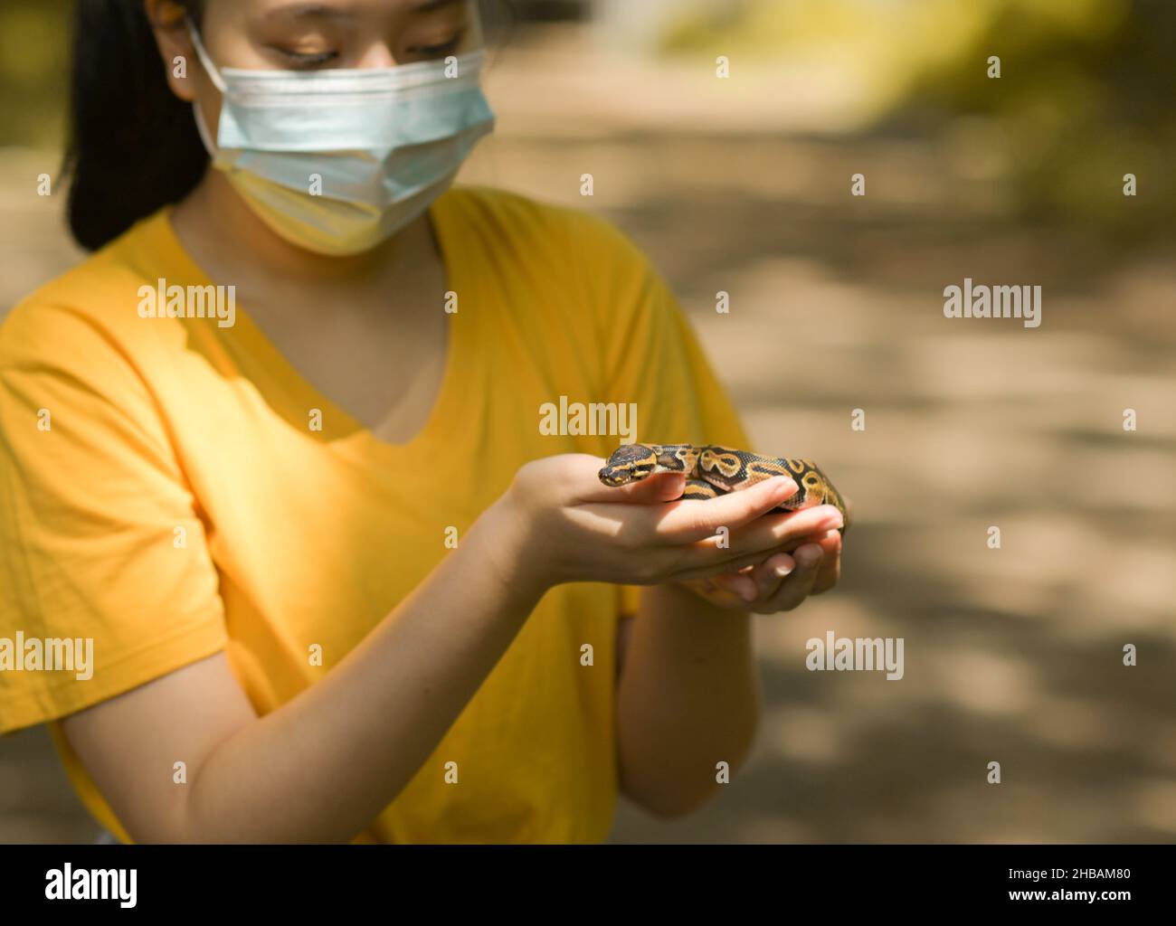 A teenage girl with a ball python in her hand, a girl in a mask and a ...