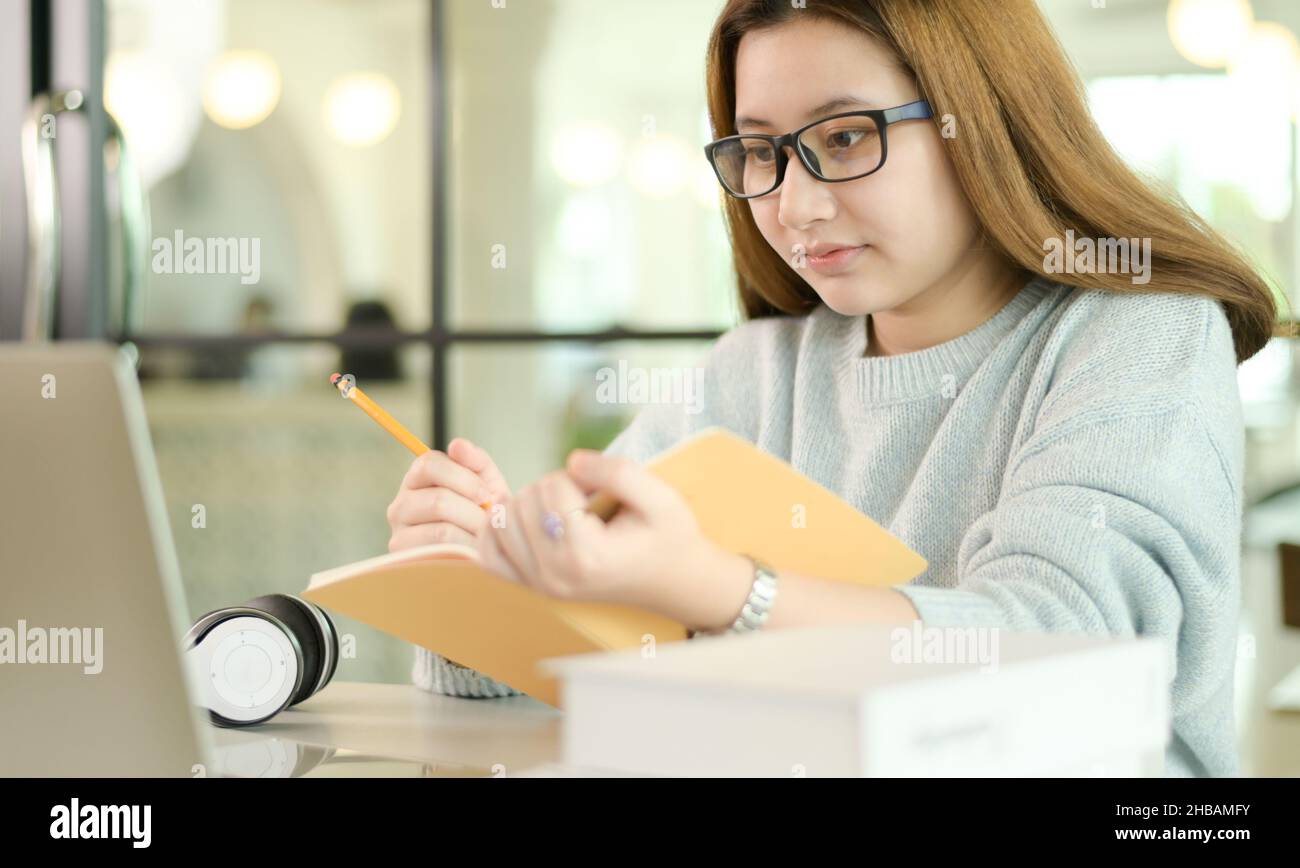 A teenage student eagerly taking notes from her laptop, wearing a gray ...