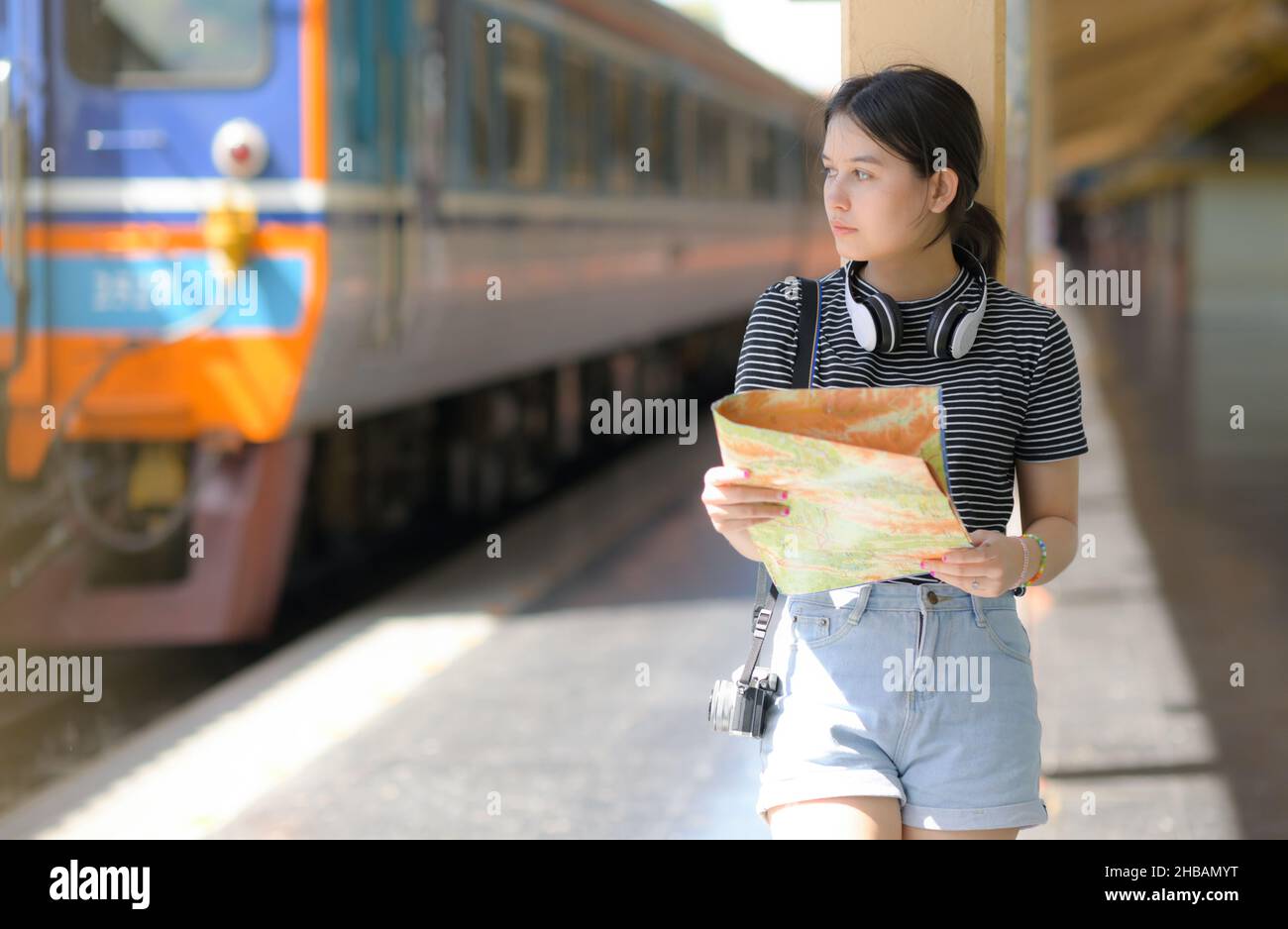 A young European girl traveler holding a map standing on the train ...