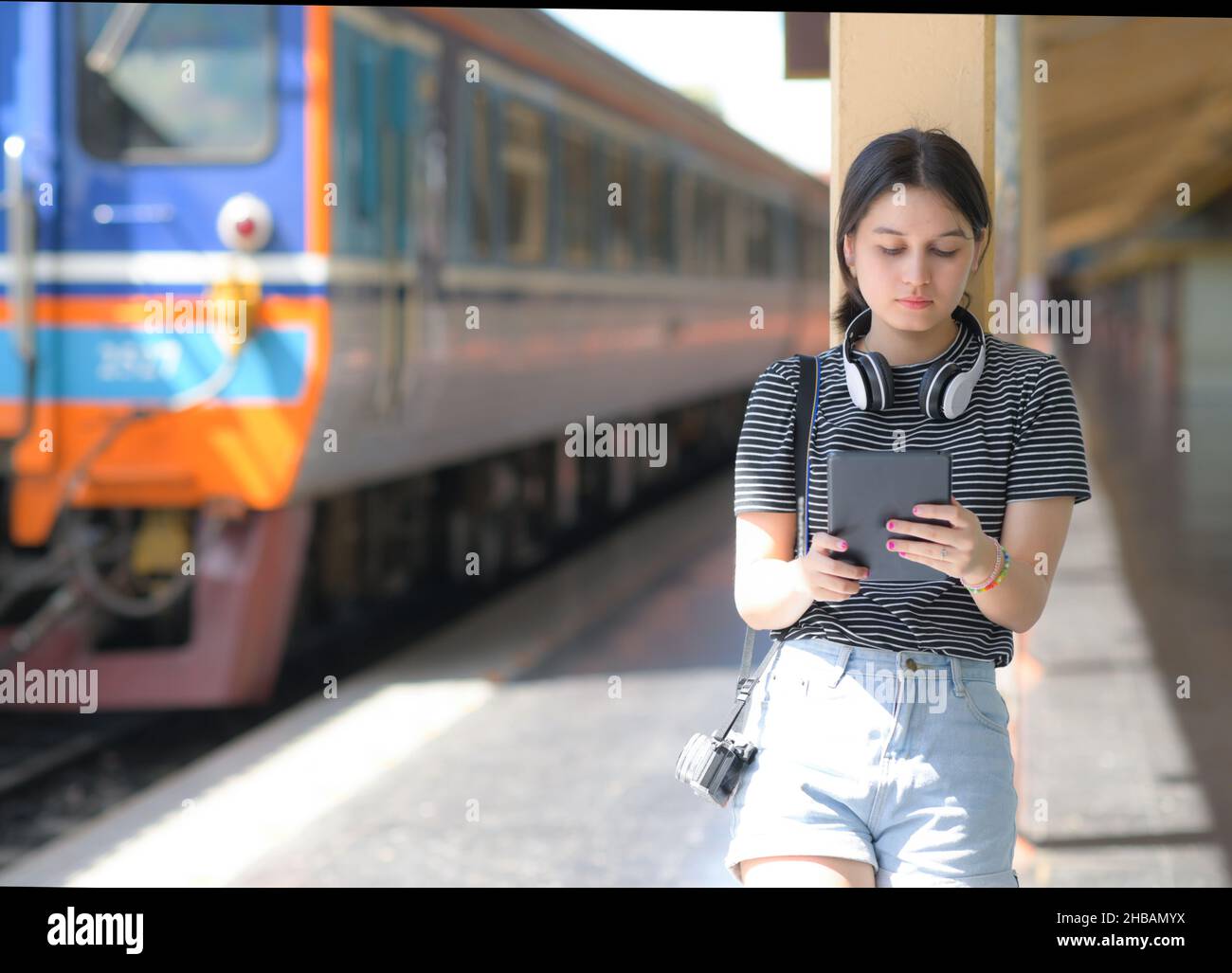 Young European female traveler holding a tablet standing on a train ...
