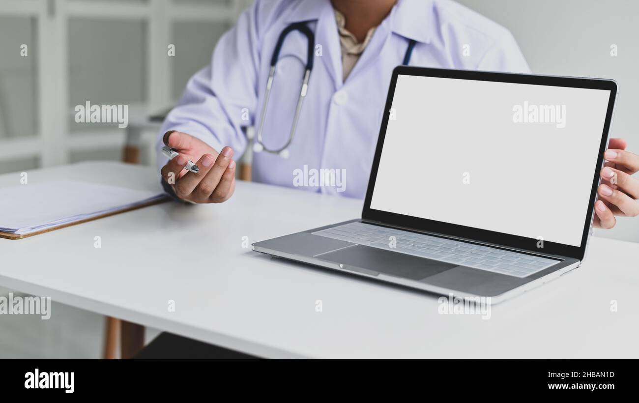 A man wearing medical uniform holding pen with a blank laptop screen in ...