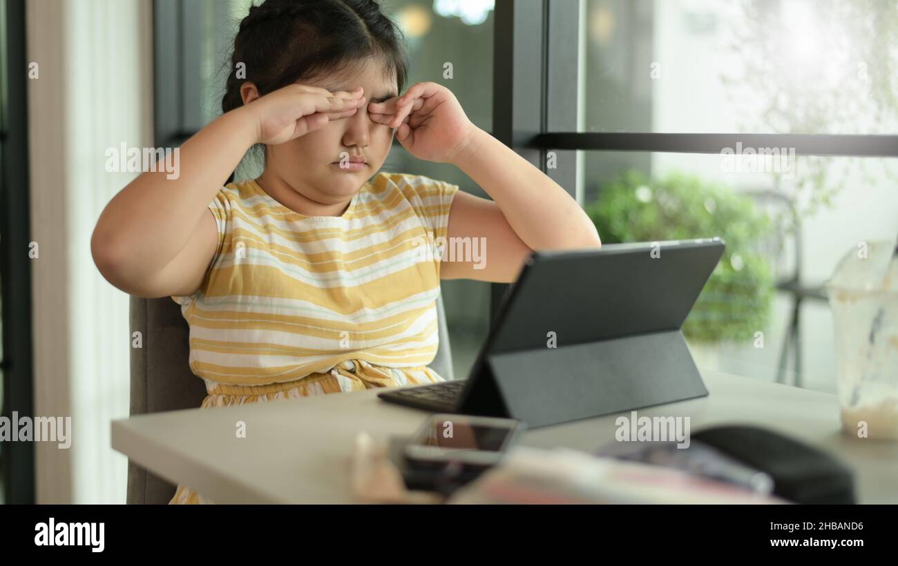 Asian child girl closes her eyes to rest from using tablet, eyes ...