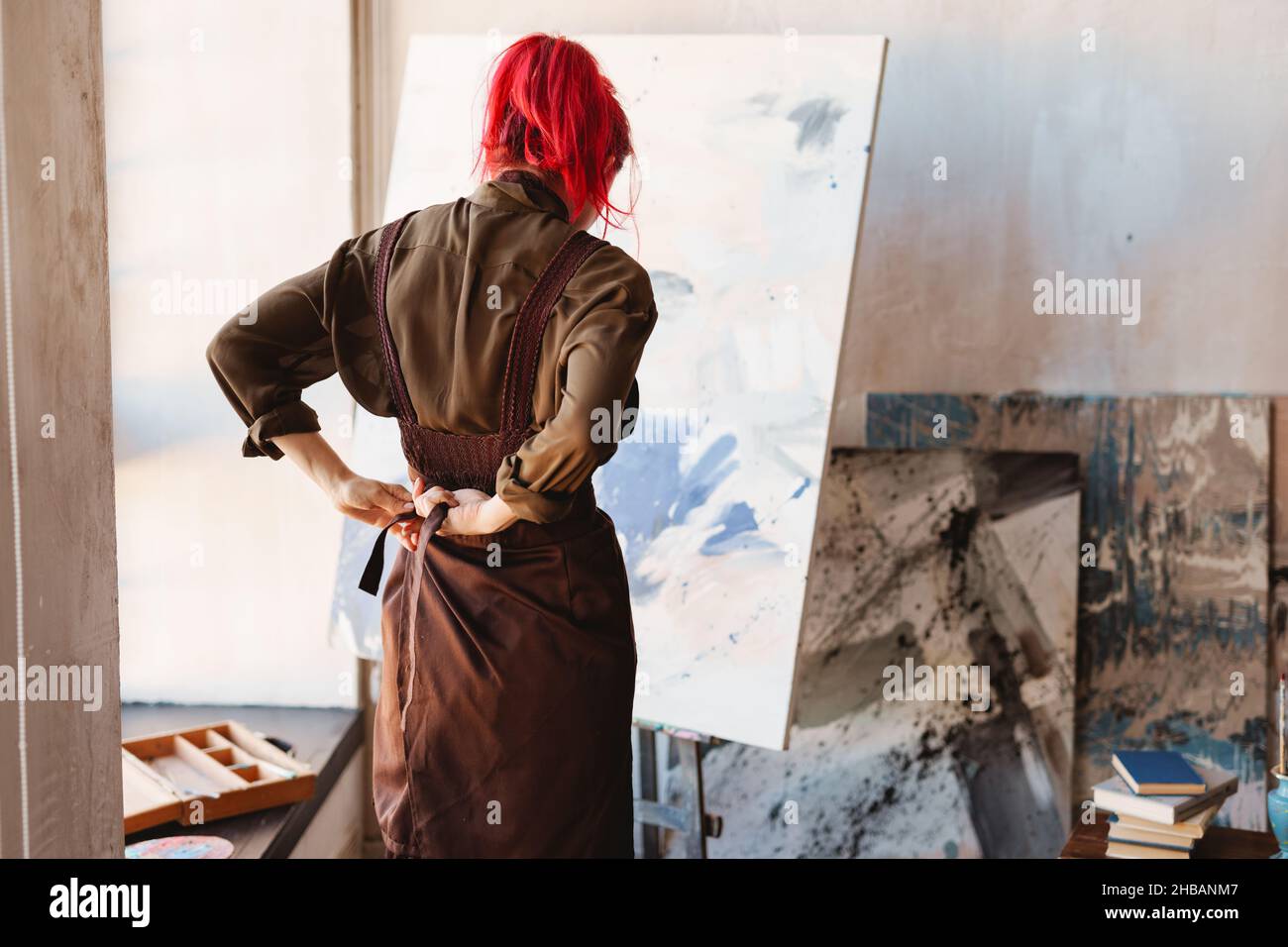Young white woman painter in an art studio, using laptop computer for ...