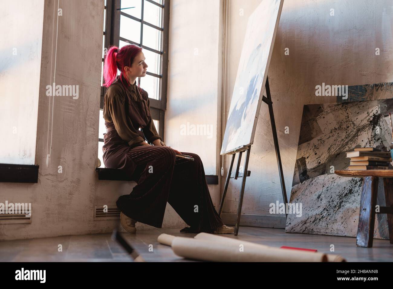 Young white woman painter in an art studio, using laptop computer for ...