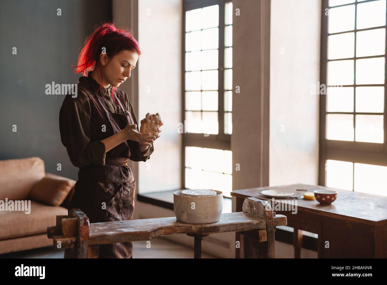 Young woman sculptor artist creating a bust sculpture with clay in an ...