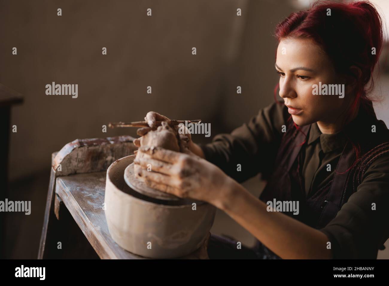 Young woman sculptor artist creating a bust sculpture with clay in an ...
