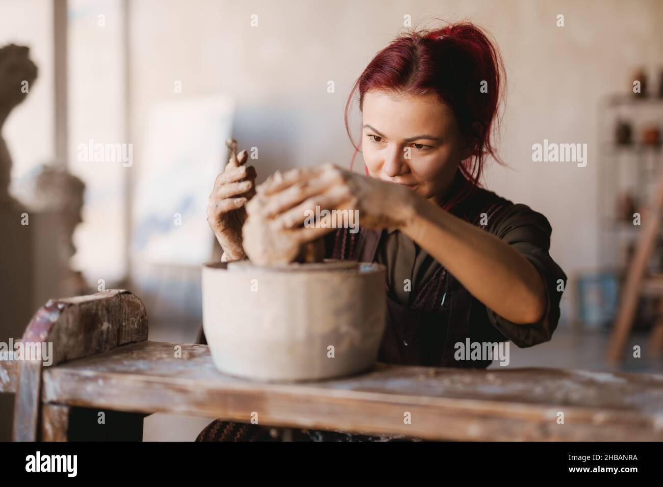 Young woman sculptor artist creating a bust sculpture with clay in an ...