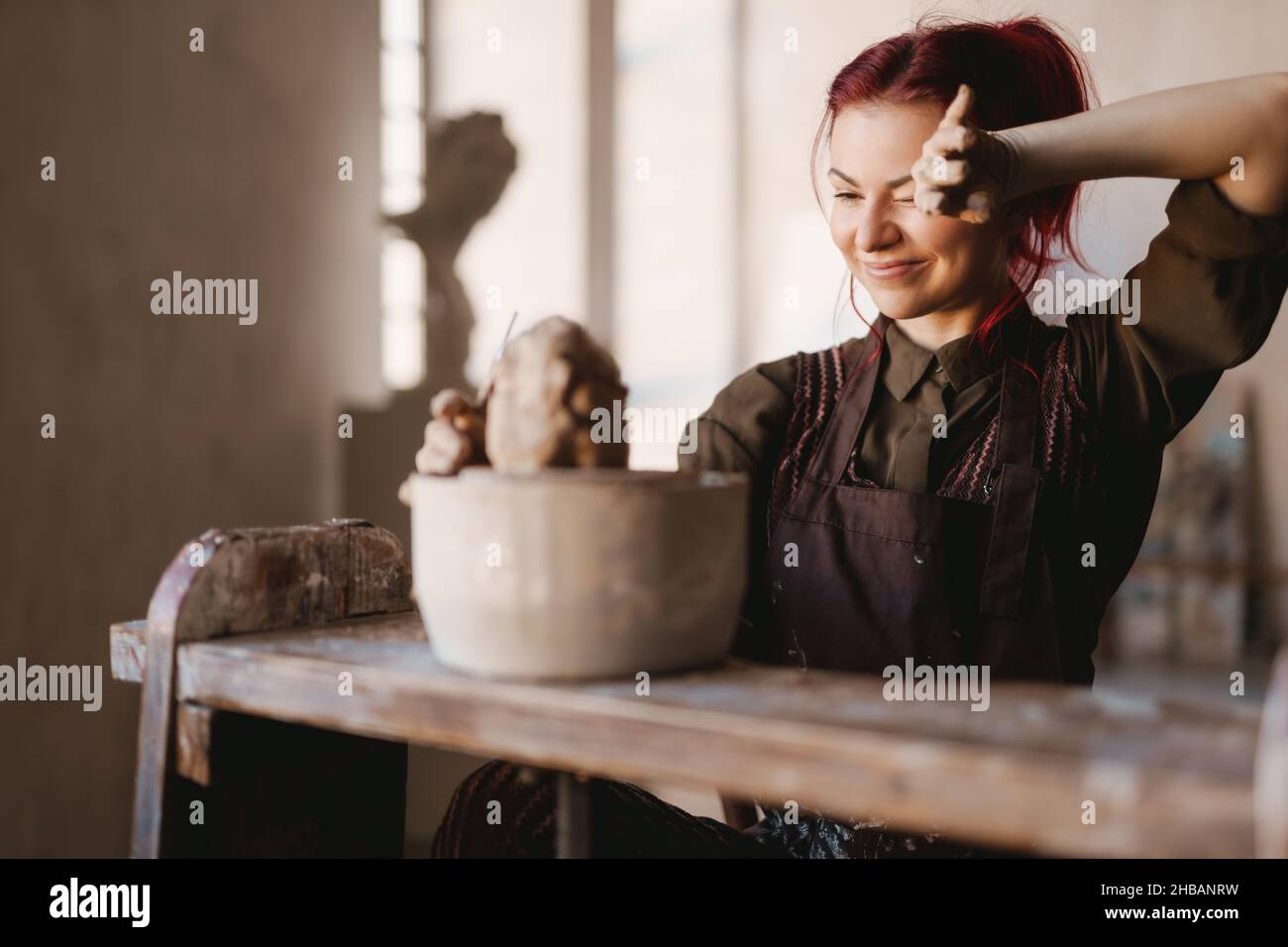 Young smiling woman sculptor artist creating a bust sculpture with clay ...