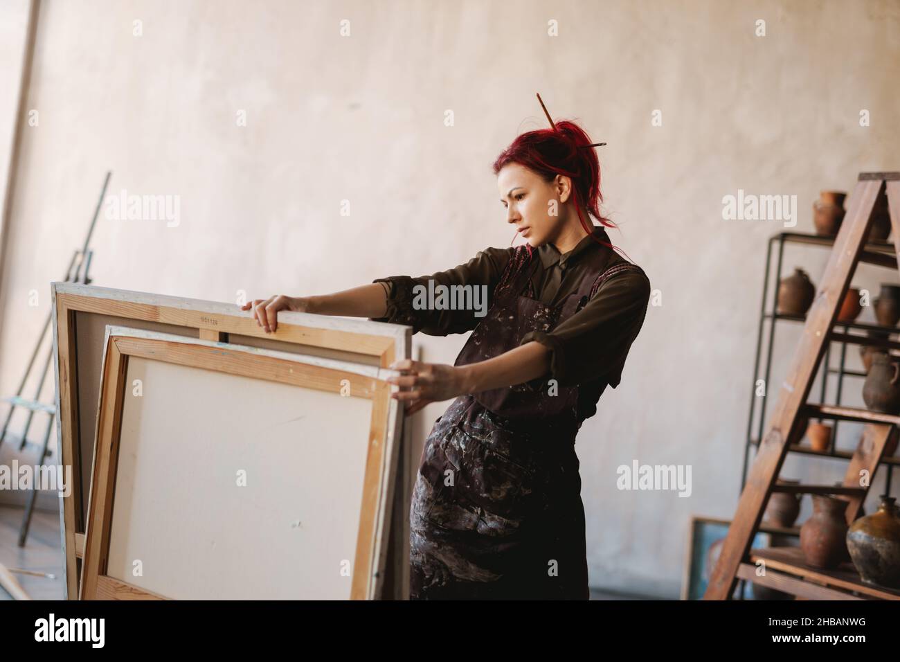 Young white woman painter in an art studio, using laptop computer for ...