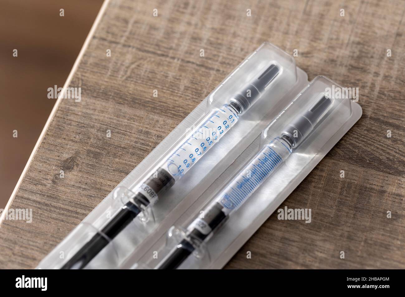 A portrait of a package with two syringes in it lying on a wooden table ...
